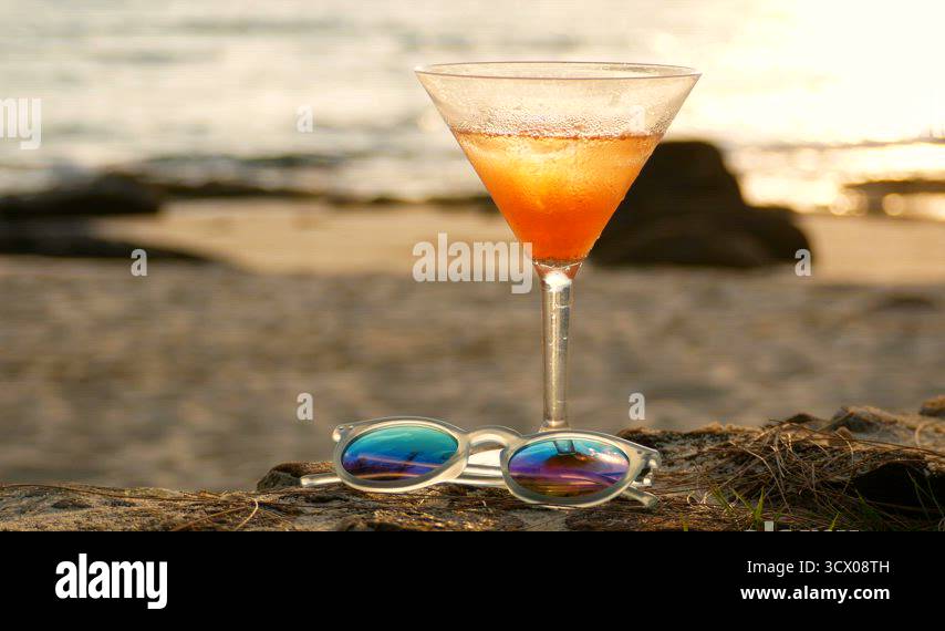 4K. cocktail glass with water droplets on the beach with golden wave ...