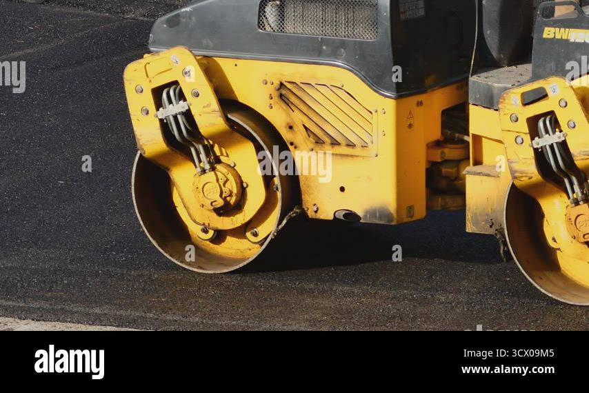 Close up shot of a pavement roller vehicle drives left and right to ...