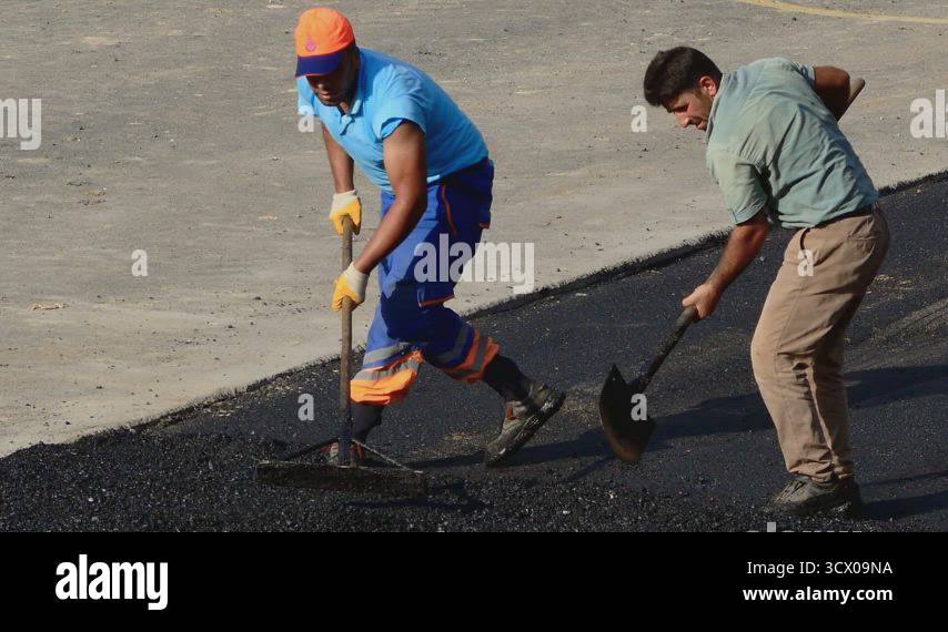 Two road builders work on the new asphalt surface Stock Video Footage ...