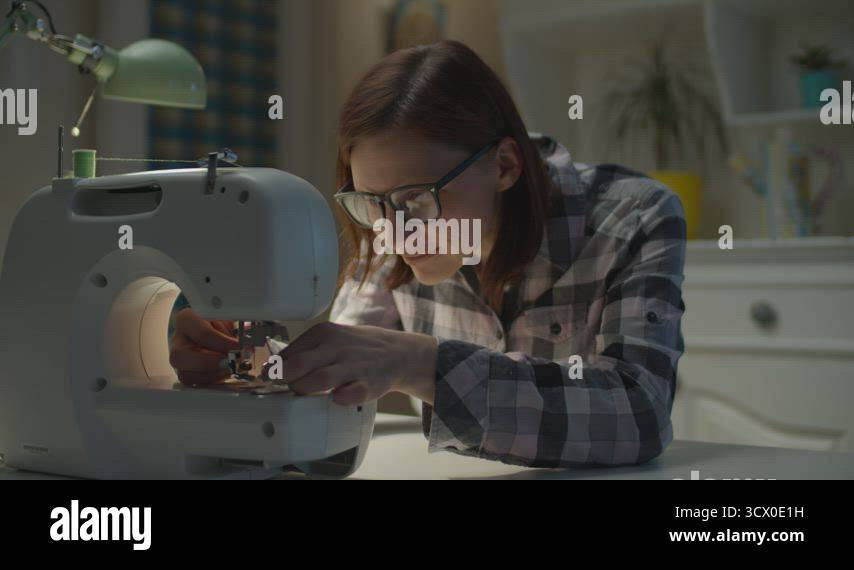 Young 30s woman threading the needle in sewing machine working at home ...