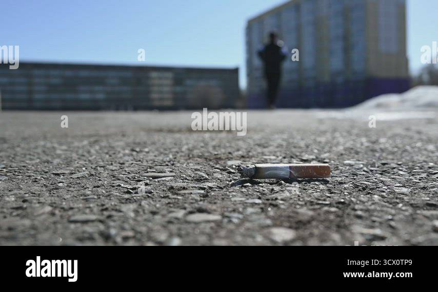 a discarded Smoking cigarette butt lies on the asphalt running track of ...