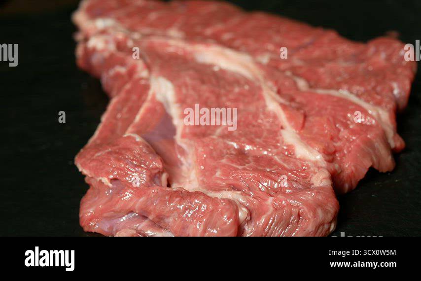 4K footage. close up of a chef hand slice raw beef with sharp knife on ...