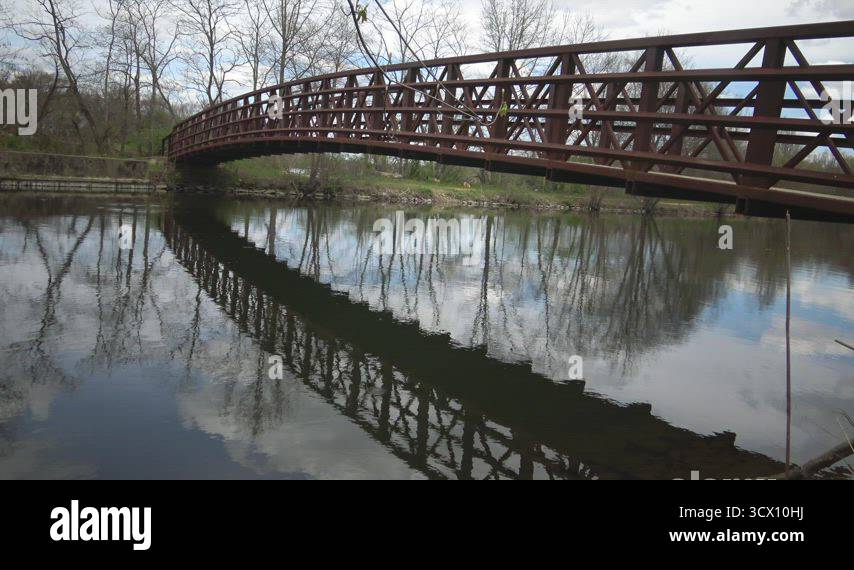Metal bridge over the canal, reflection of the bridge in the water ...