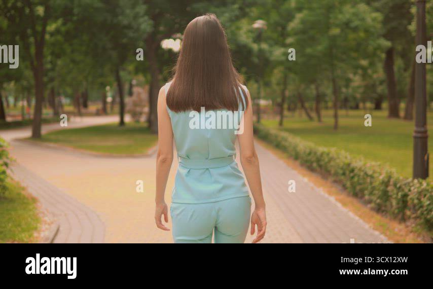 back view close up woman walking on the street in city park summer ...