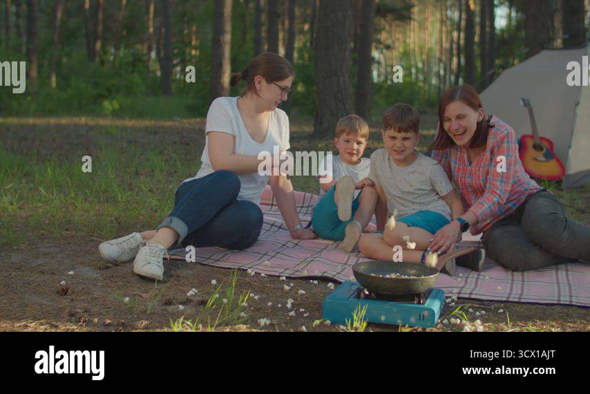 Happy family of two moms and two sons cooking pop corn on frying pan ...