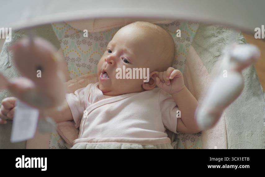 Yawning baby girl in child rocker with toys Stock Video Footage - Alamy