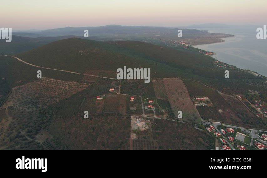 Flying over green landscape with plains and hills in coastal town ...