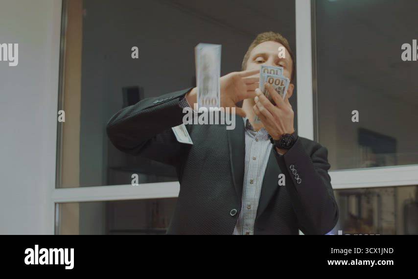 Young successful business man throwing money in slowmo at night in ...
