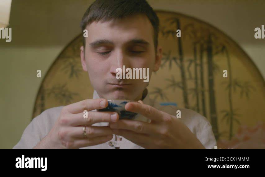 Portrait young man drinking tea from bowl and enjoying flavour and ...