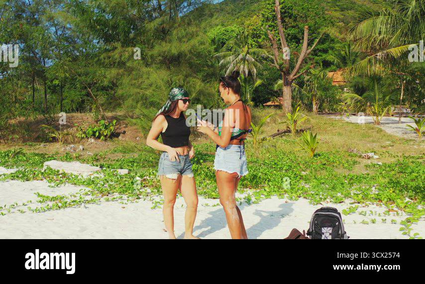 Modern smiling girls on holiday in the sun at the beach on paradise ...