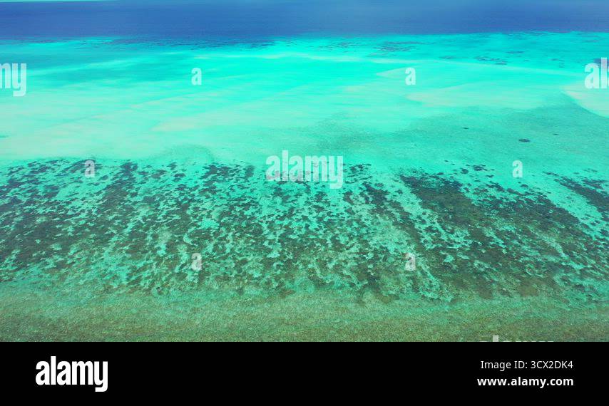 Wide above island view of a sandy white paradise beach and aqua blue ...