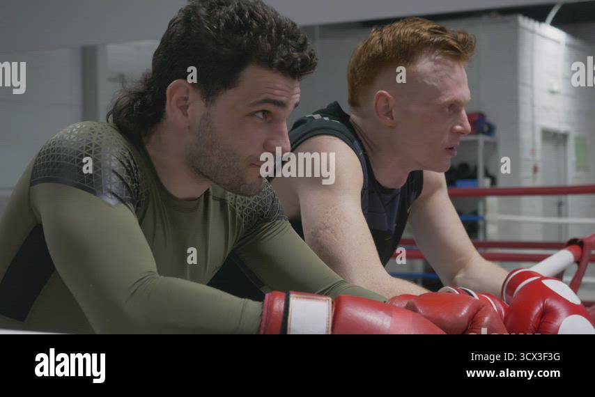 Two boxer in boxing gloves resting after training on ring in fight club ...