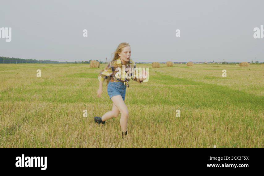 Teenager girl running on harvesting field on hay stack landscape in ...