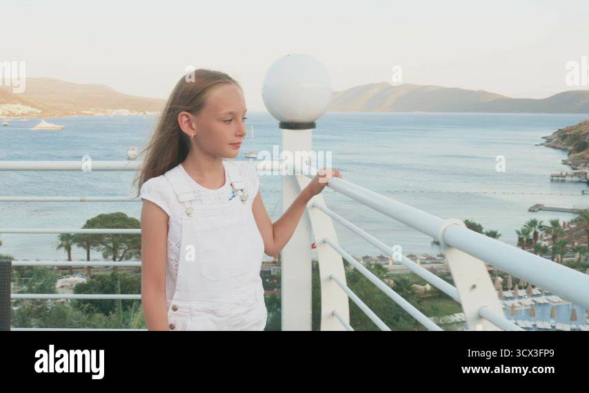Teenager girl walking on outdoor terrace with sea and mountain ...