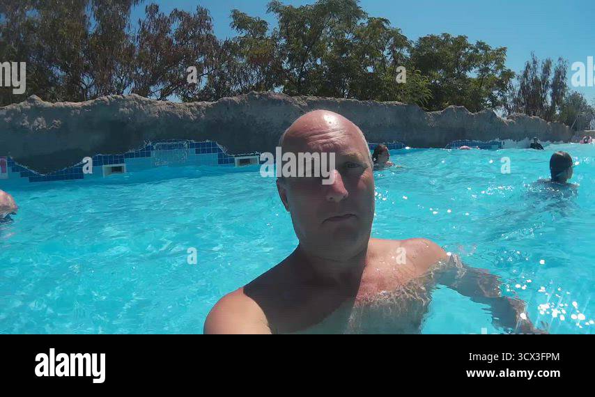 Bald man diving underwater swimming pool and blowing air bubble ...
