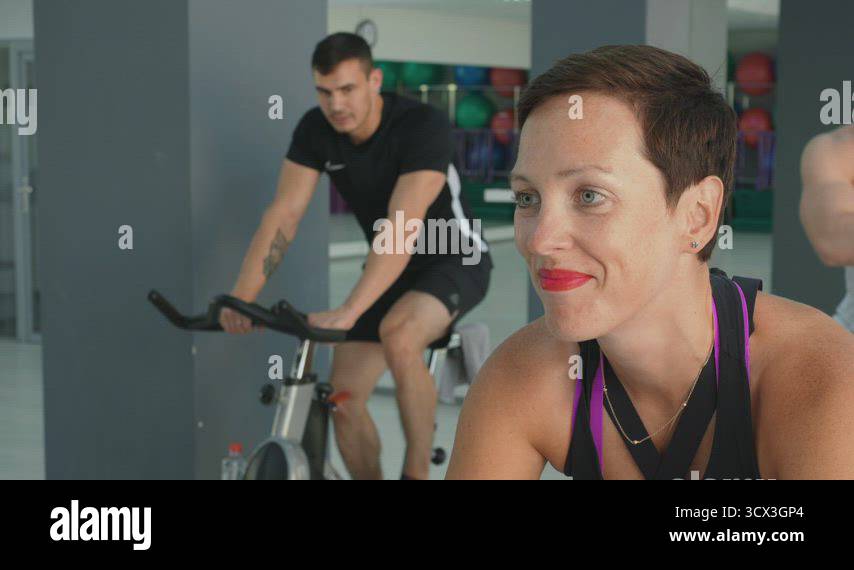 Smiling woman training on static bike at cycling class. Portrait fit ...