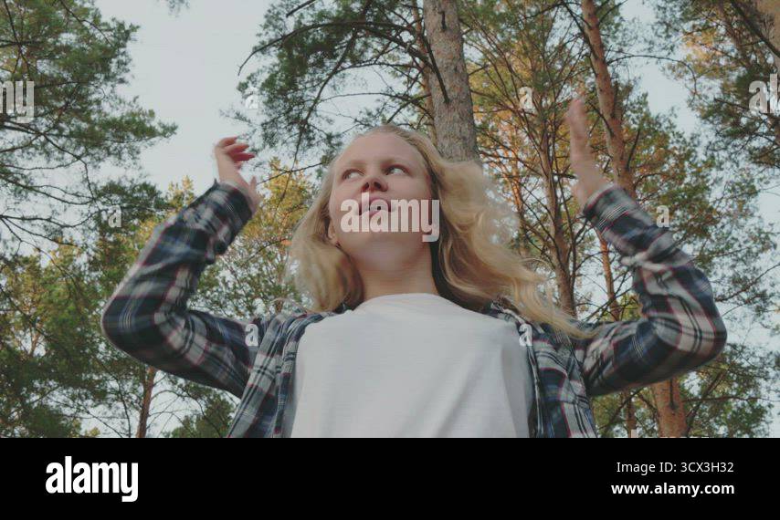 Happy girl teenager dancing with head and hands in pine forest. Smiling ...