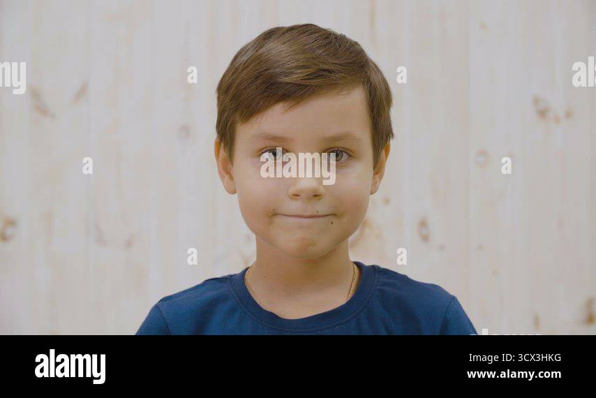 Young boy smiling only lips front camera in light studio. Close up ...