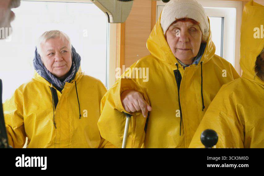 Group senior woman in yellow waterproof jacket on passengers ship board ...