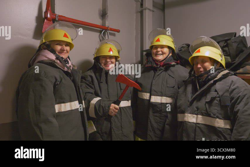 Firefighter woman in a yellow raincoat extinguishes the fire in the ...