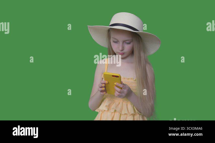 Young girl in hat and yellow dress using mobile phone on transparent ...