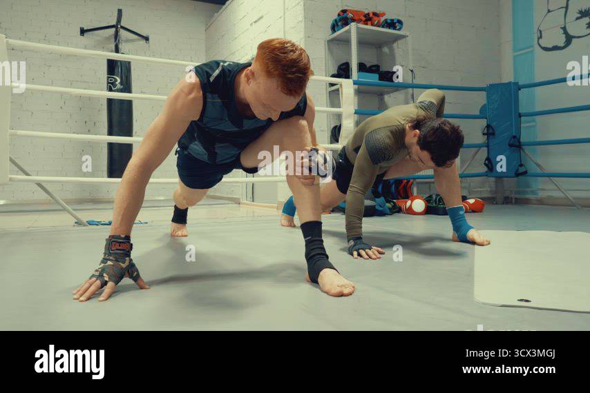 Two kickboxer stretching legs while preparing to fight training on ring ...