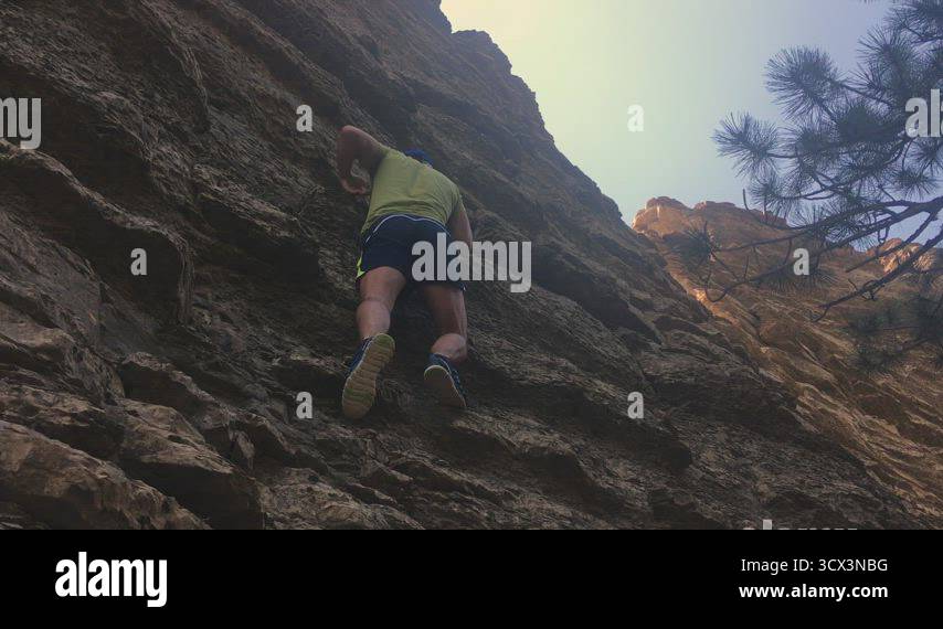 Climber man climbing on mountain while rockfall low angle view ...