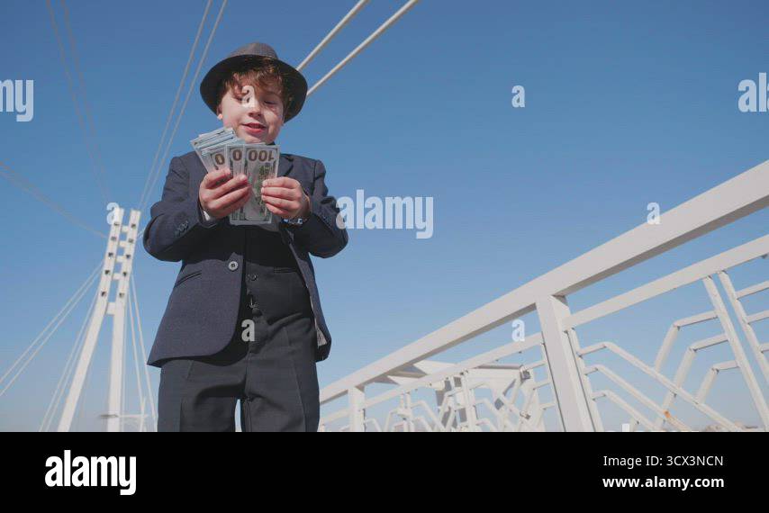 Carefree young boy throwing money cash from bridge low angle view. Young boy looks like ...