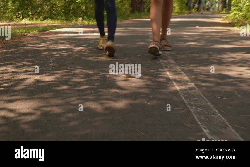 Two teens girls friend walking in park together holding hands, legs ...