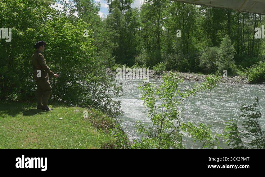 man with old french military uniform, smoking cigarette near the river ...