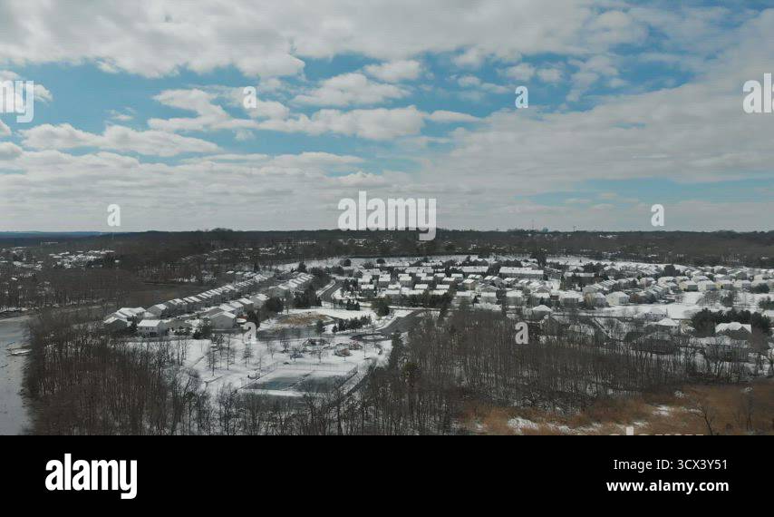 Drone footage flying over small town neighborhood, trees covered with ...