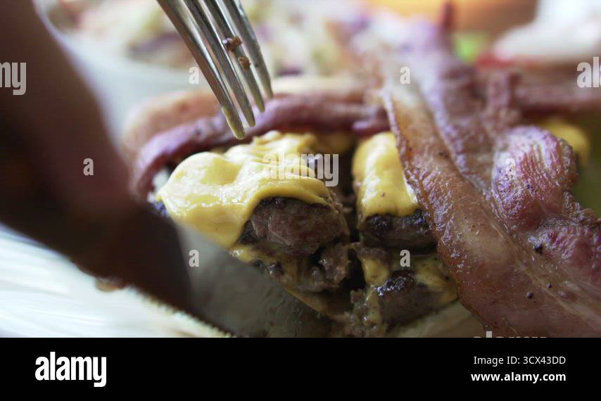 Slow motion 120 fps knife cutting juicy hot bacon beef, cheese ...