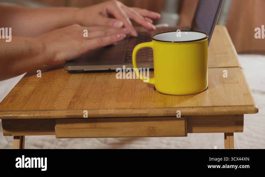 two female hands and a laptop on a wooden bedside table, a girl working ...