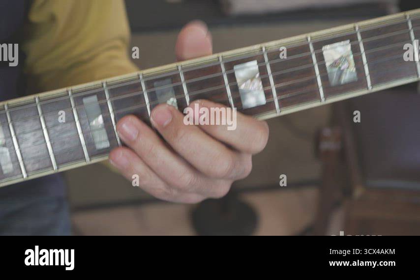 A close-up of a guitar master's hand sliding on the neck playing chords ...