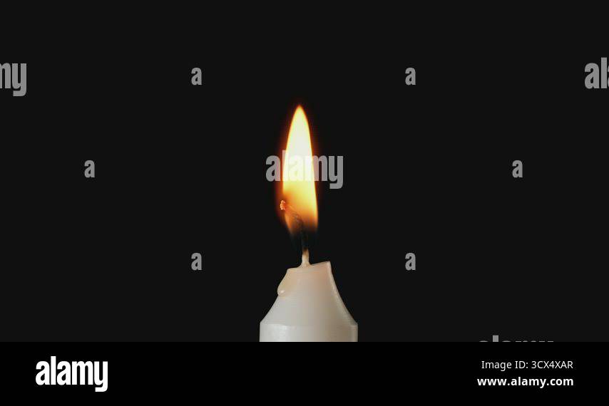 burning white wax candle on a black background, hand extinguishes flame ...