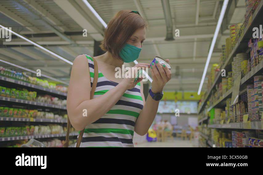 30s woman in face protective mask reading grocery ingredients on can ...