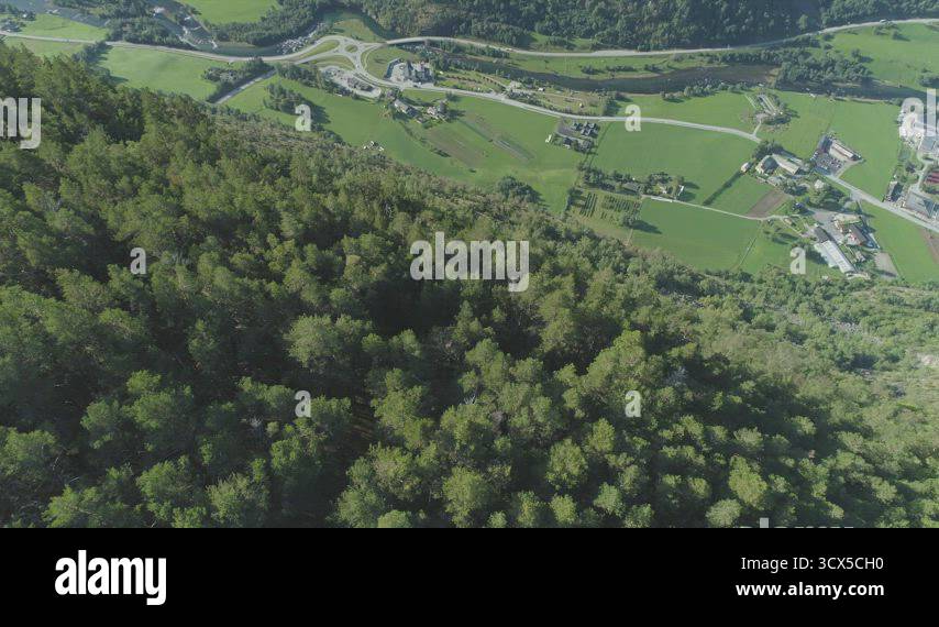 Flying over Mountain Slope with Green Trees and Village in Norway at ...