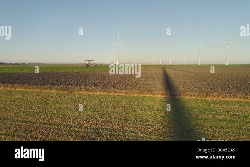 AERIAL WS Field with traditional windmill and wind turbines at sunset ...