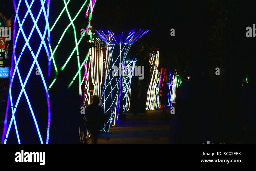 blur pattaya city and decorate rainbow LED light on palm trees and ...