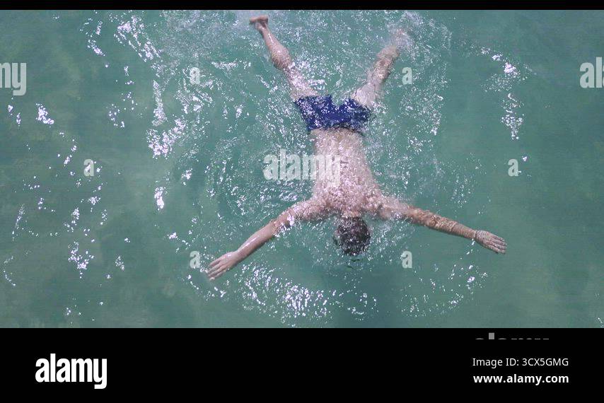 Male body floating in water. Aerial drone shot of drowned guy in the ...