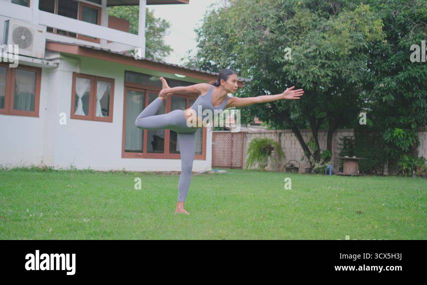 Wide shot of woman action of yoga posture King Dancer Pose in her house ...