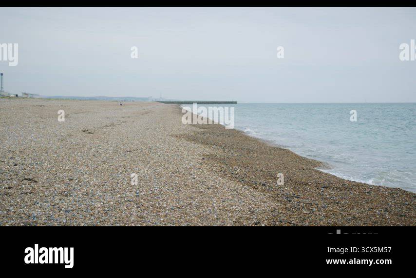 WS PAN SLO MO Man with surfboard standing on beach and looking at sea ...