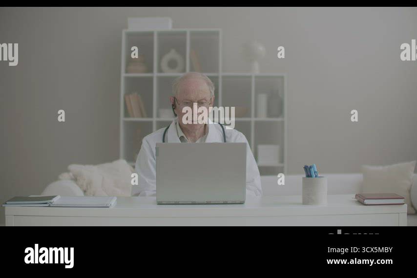 aged male physician is working remotely from his office in clinic ...