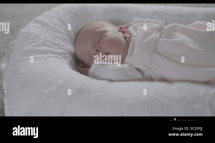 High angle close up of sleeping newborn baby girl wearing pink babygro ...