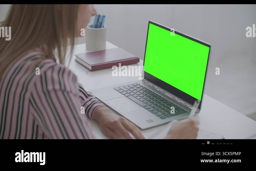 e-education, woman is viewing on laptop with green screen for chroma ...