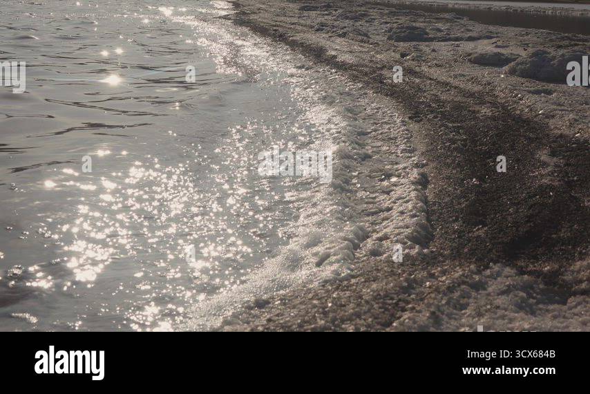 Salt lake, salt crystals. Salt water waves crash onto the shore in the ...