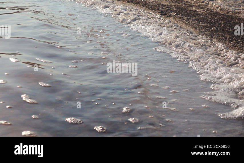 Salt lake, salt crystals. Salt water waves crash onto the shore in the ...