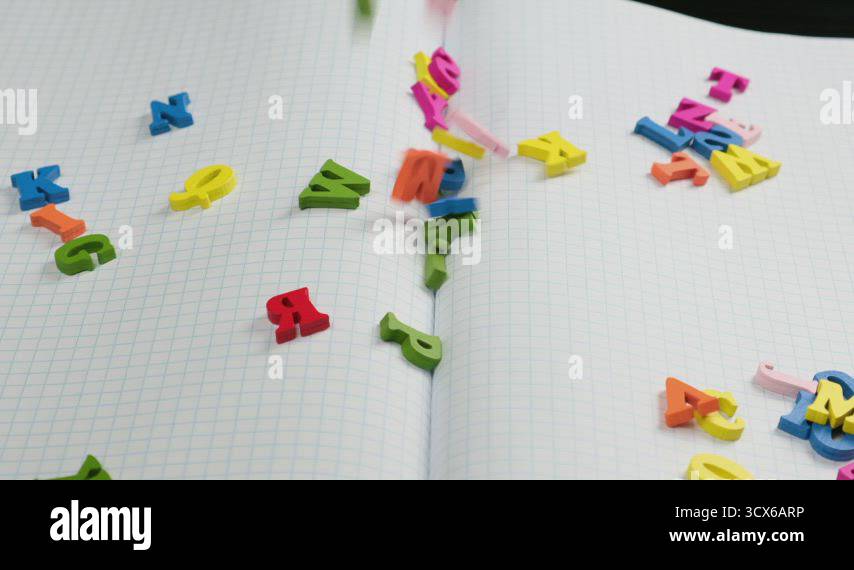 falling multicolored wooden letters of the English alphabet on a paper ...