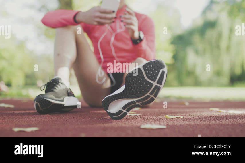 Fitness girl stretching her legs while sitting on an all weather ...