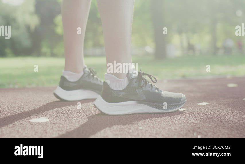 Runner girl stretching her feet and hands on an all weather synthetic ...